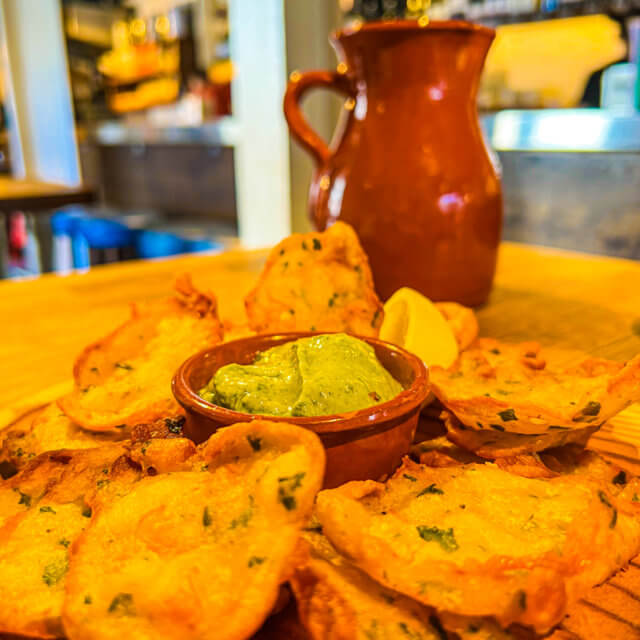 Image of prawn tortilla fritters up close with green dip in centre with ...